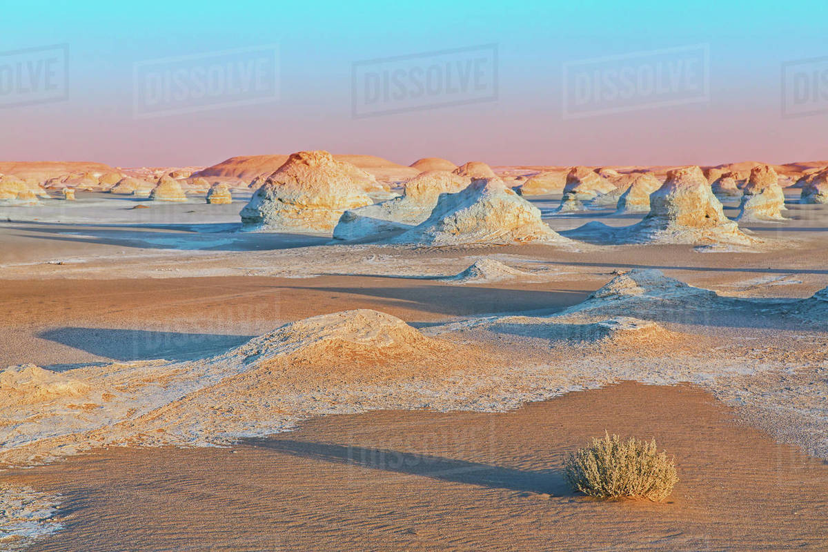 Sand and white limestone formations at sunset in a sea of sand, with ...