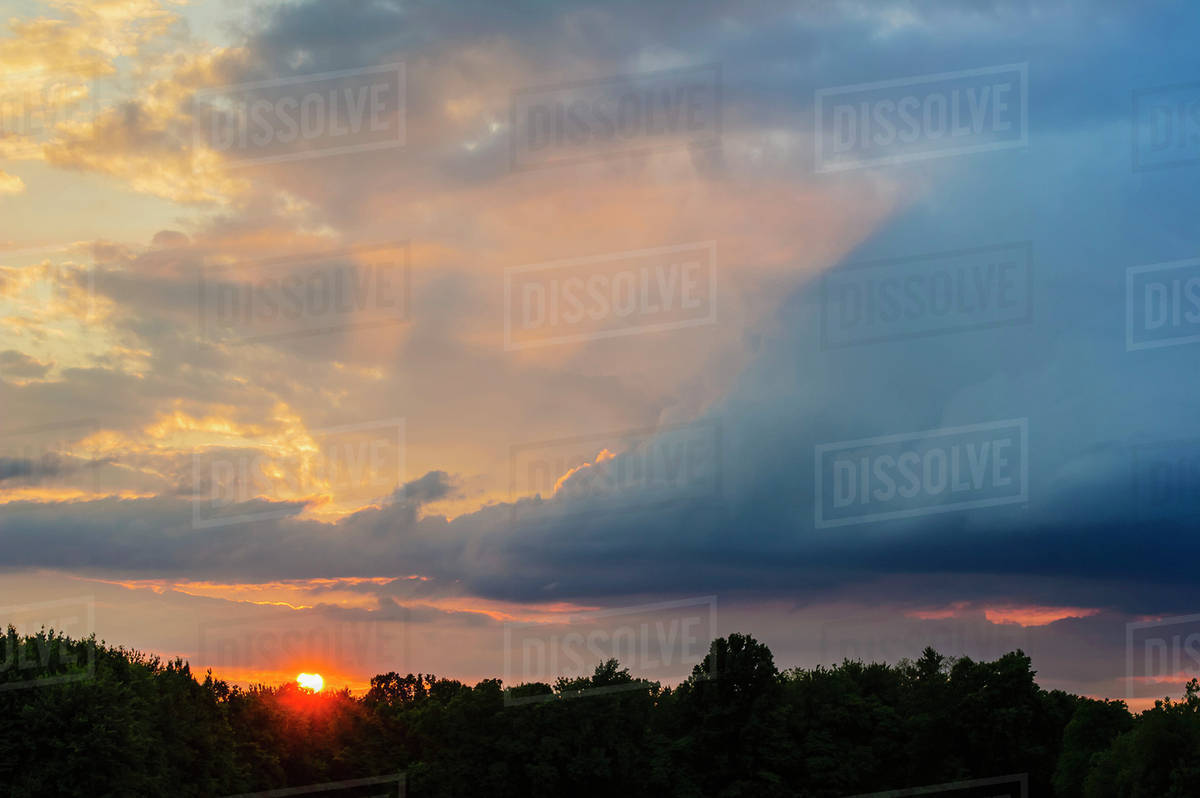 Sun setting over the trees with storm clouds in the sky;Ohio united ...