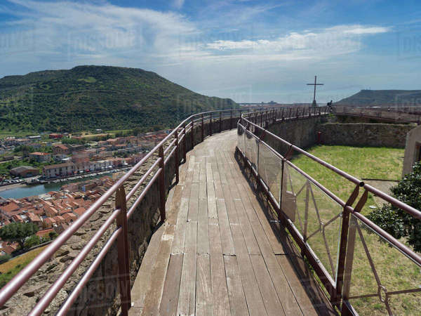 Elevated walkway on a stone wall overlooking the town of Bosa in Italy ...
