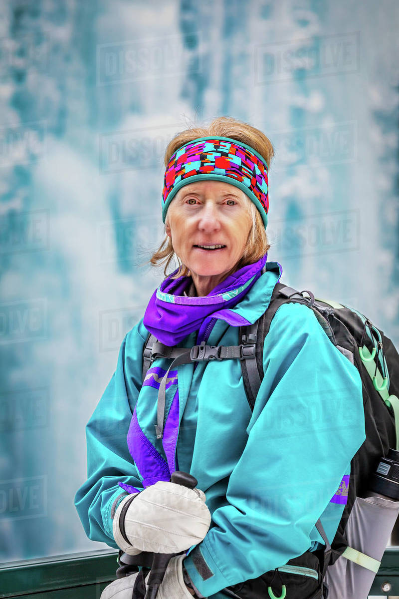 Portrait of a female hiker in the winter with a frozen ice falls in the ...