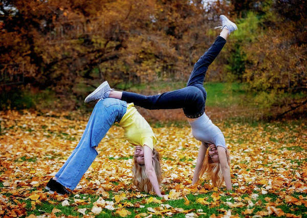 Two teenage girls playing around with acrobatic positions in a city ...