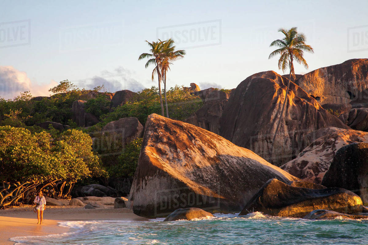 Woman walking along the famous beach of The Baths against the large ...