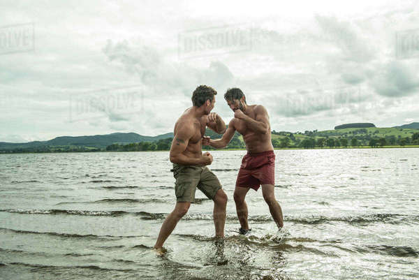 Two bare chested man shadow boxing in the shallow water of Bala Lake in ...