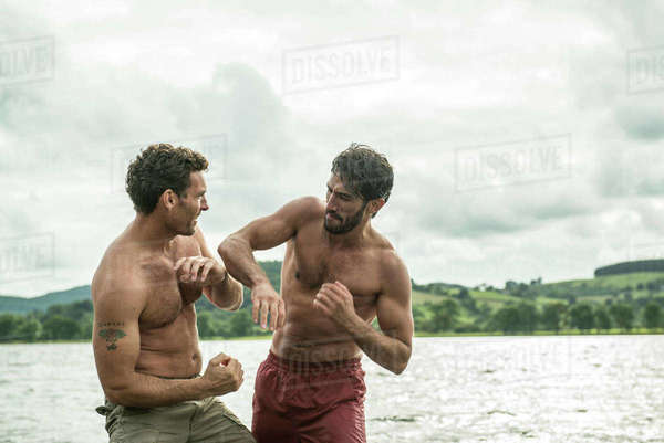 Two bare chested man shadow boxing in the shallow water of Bala Lake in ...