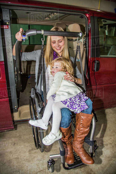 Young disabled mother with her daughter using a wheelchair powered ...