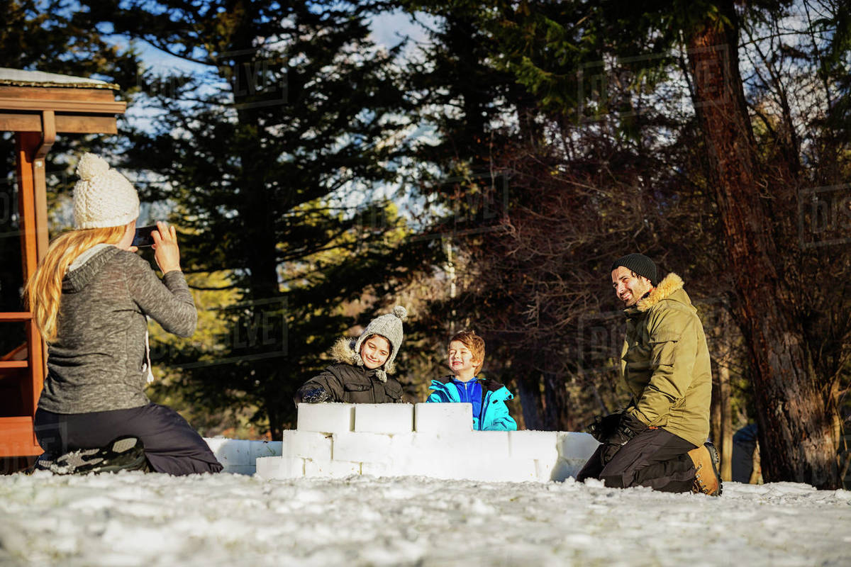 A Mother Takes A Picture Of A Father And Two Sons Building An Igloo ...