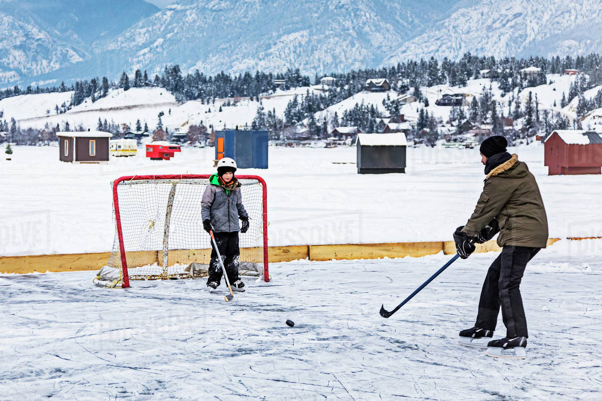 Father and his son playing hockey on a frozen Windermere Lake during ...