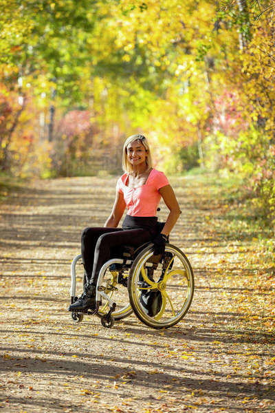 Portrait of a young paraplegic woman in her wheelchair on a trail in a ...