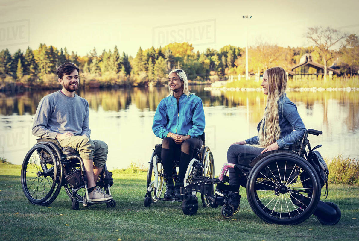 Group of three young paraplegics in their wheelchairs visiting together ...