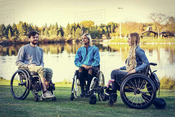 Group of three young paraplegics in their wheelchairs visiting together ...