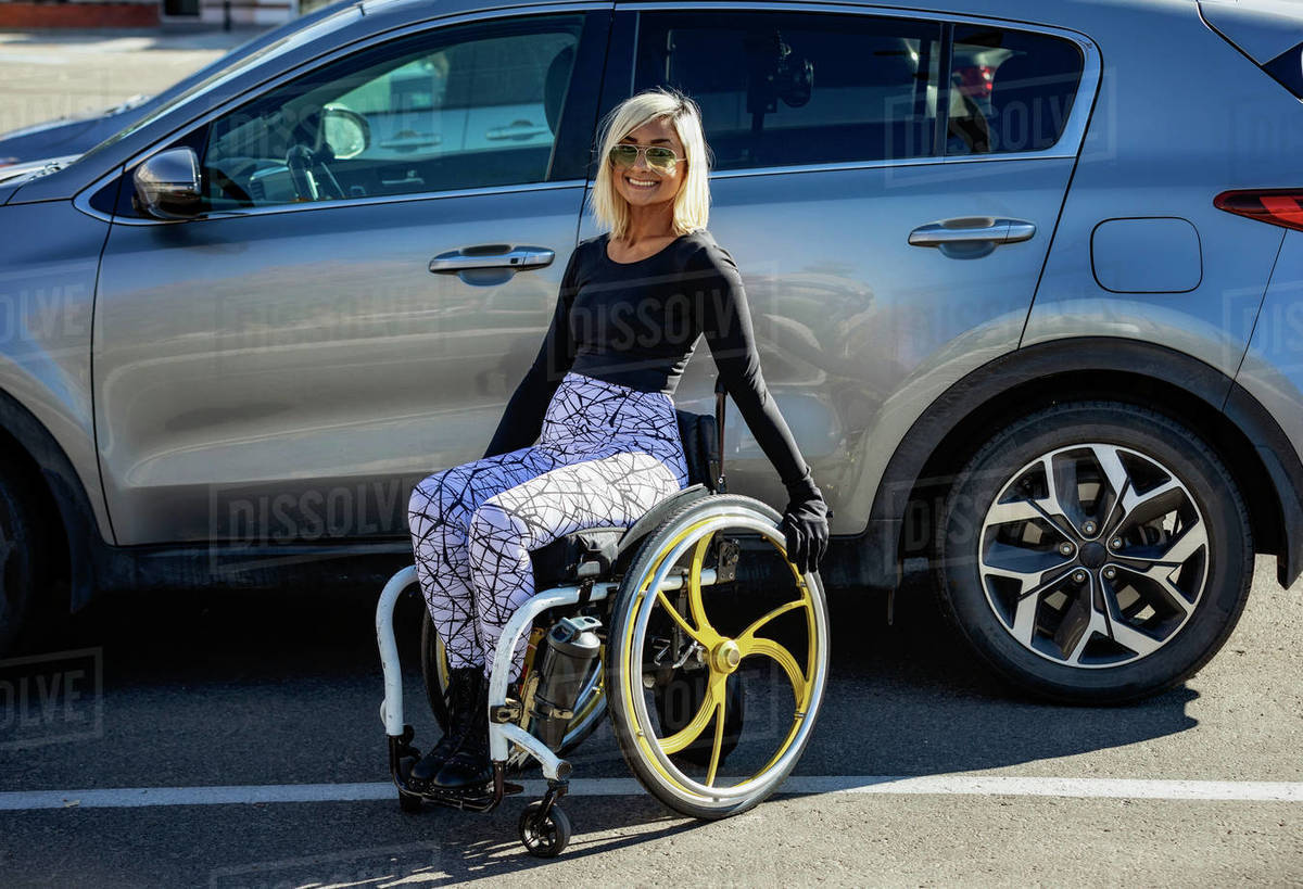 Young paraplegic woman in her wheelchair outside her adapted vehicle in ...