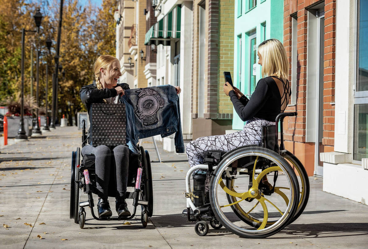 Young paraplegic friends spending time together shopping outside in a ...