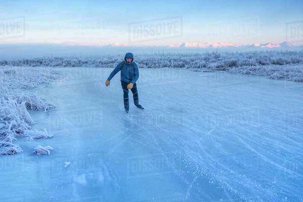 A caucasian man backcountry ice skating, nordic blading, on wild ice of ...