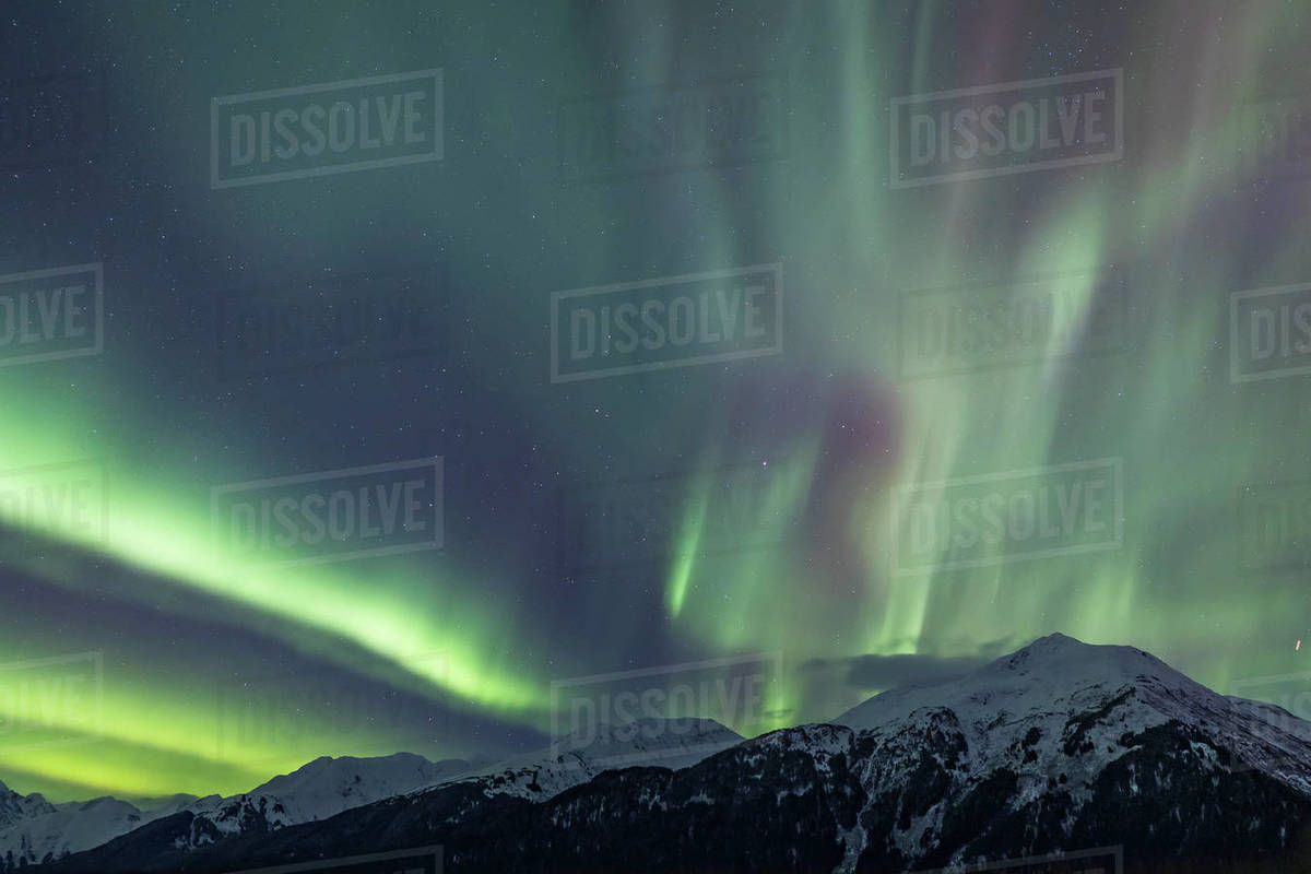 Northern lights illuminate the night sky above the mountains near ...