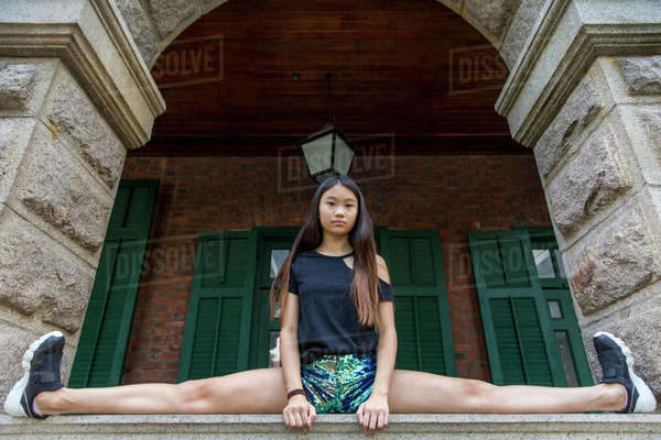 Preteen girl in a splits position on a ledge under an archway; Hong ...
