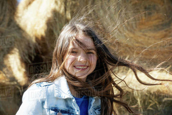 Portrait of a carefree young girl with windblown long brunette hair ...
