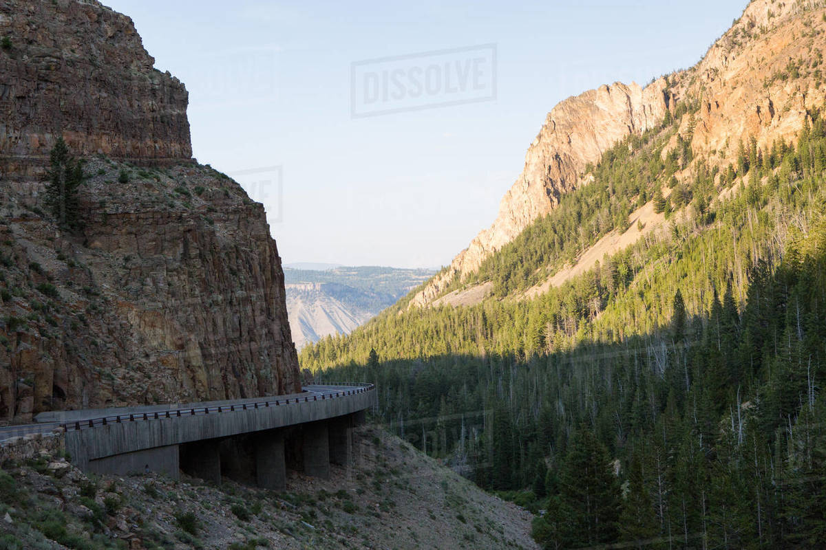 A winding road curves through a steep valley in Yellowstone National ...