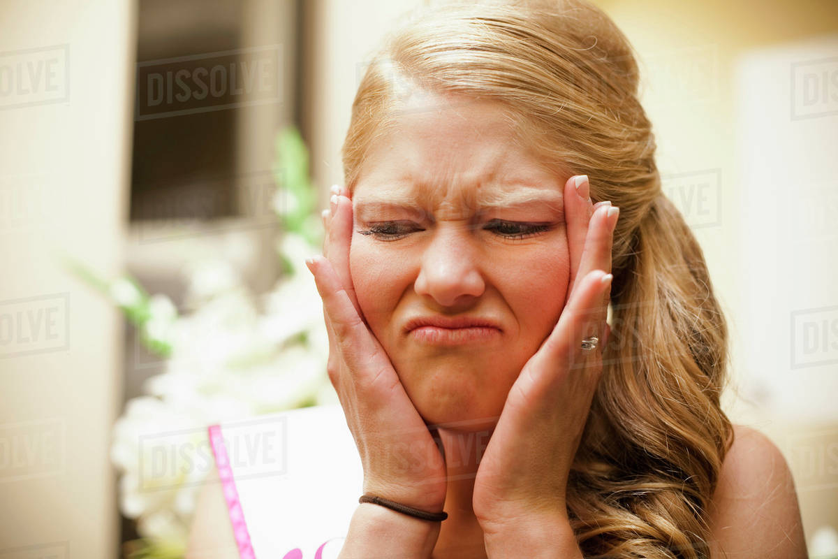 A Woman Holding Her Face In Her Hands With An Unpleasant Expression ...