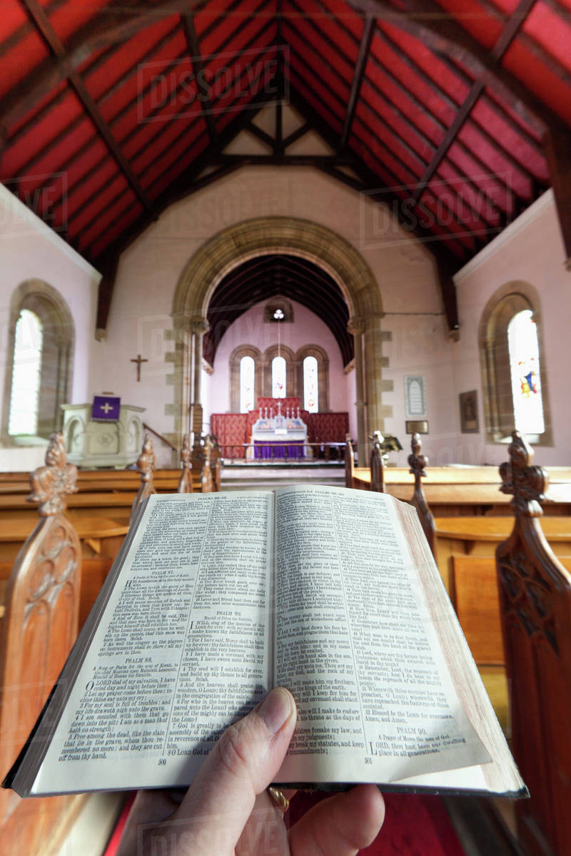 A Hand Holds A Small Open Bible At The Back Of A Church; Howick ...