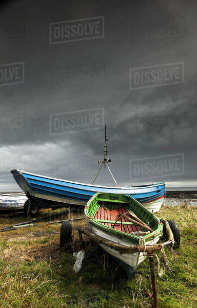 Rowboats sitting on trailers on the shore under storm clouds;Boulmer ...