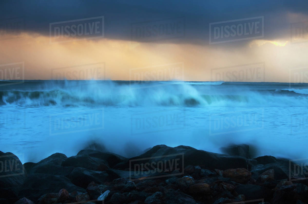 Mist above the splashing waves along the coast at sunset;Kirra gold ...