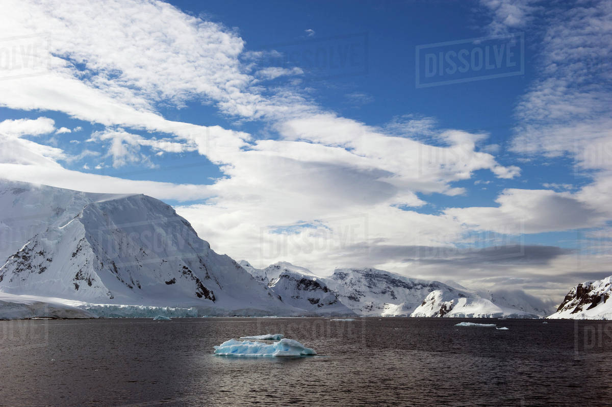 Glaciers snow covered mountains and an iceberg along the coast of the ...