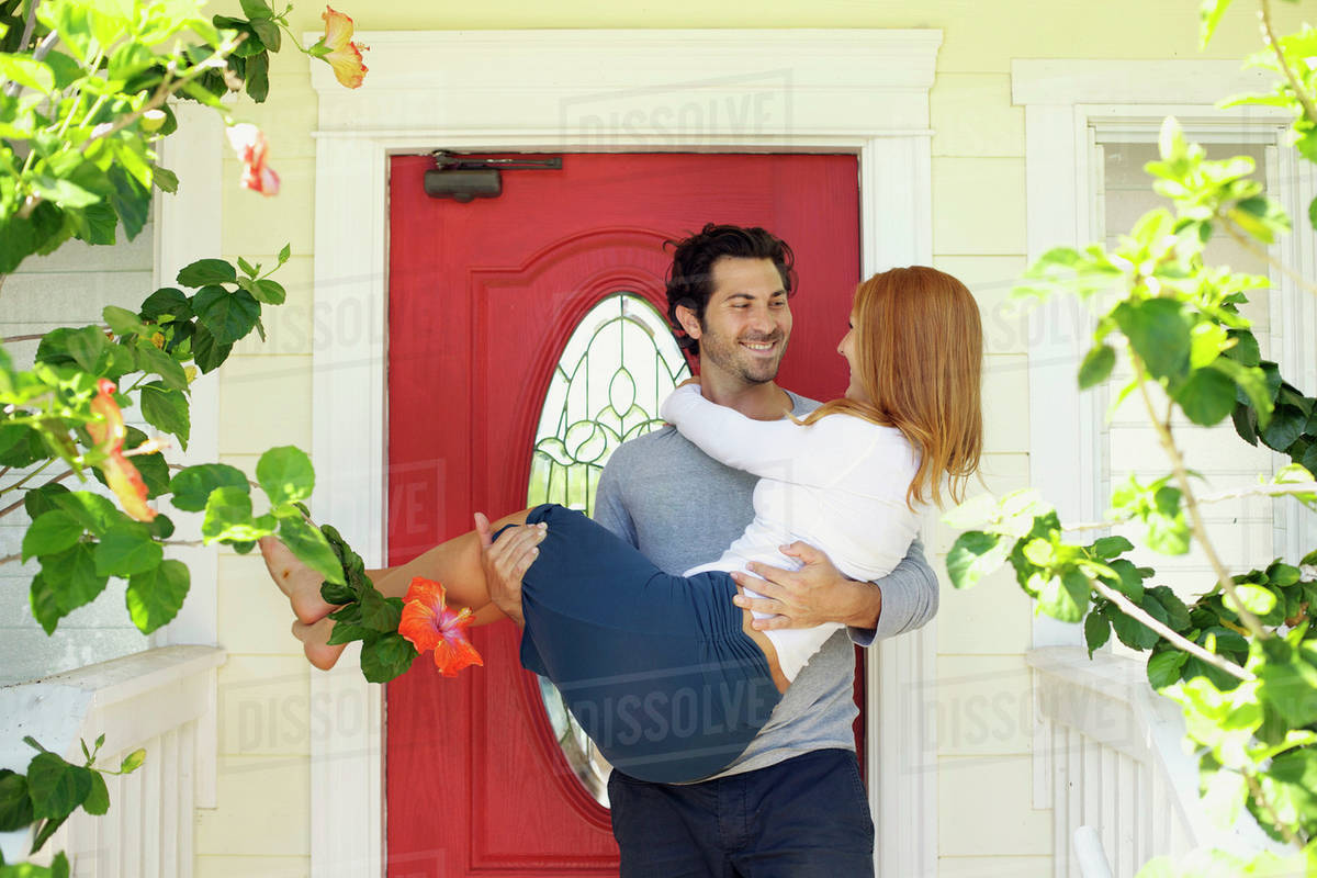 A man carries a woman over the threshold at the front door;Wailua kauai ...
