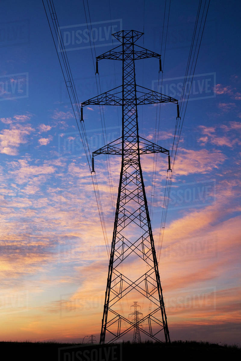 Large metal electric tower at sunrise with dramatic colourful clouds ...