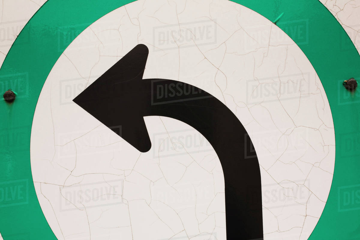Black left turn directional arrow on a white and green traffic sign ...