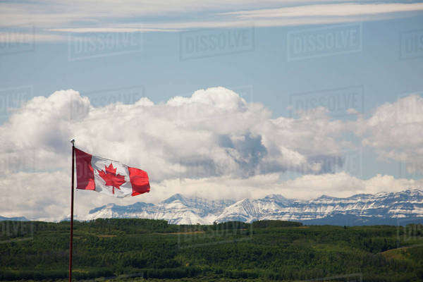 Canadian Flag Blowing In The Wind With Snowy Mountains In The Distance ...