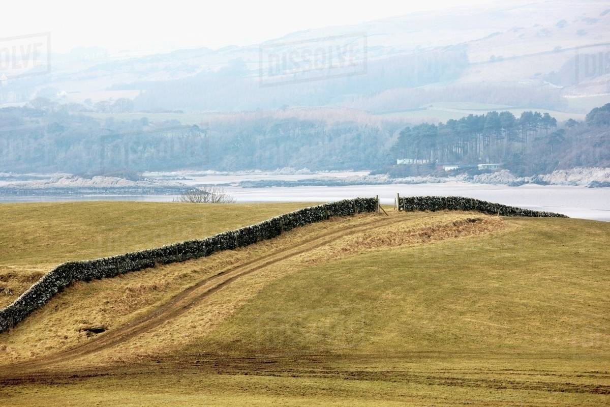 Dumfries, Scotland; A Stone Fence Across A Field - Stock Photo - Dissolve