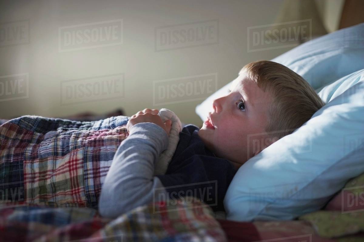A Boy Laying Awake In Bed - Stock Photo - Dissolve