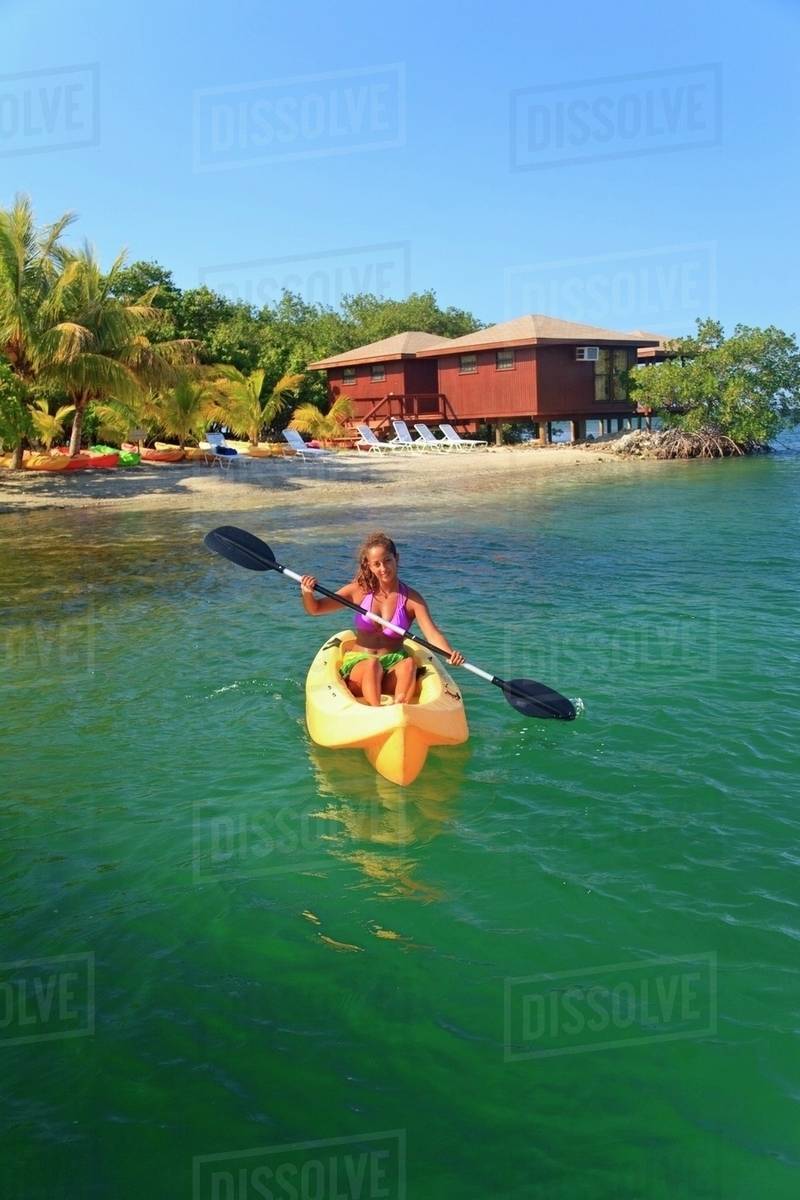 Roatan, Bay Islands, Honduras; A Young Woman Paddling A Kayak At ...