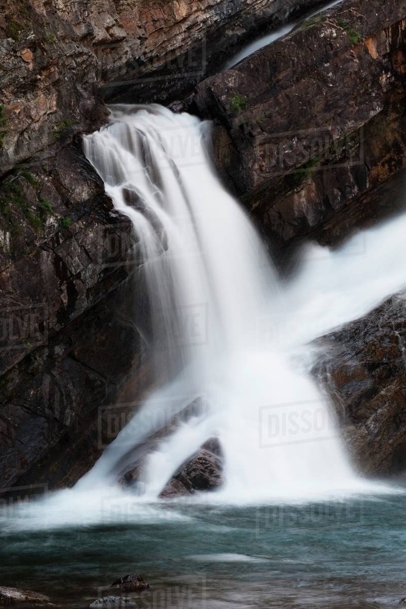 Waterfalls Coming Out Of A Rock Cliff; Waterton, Alberta, Canada ...