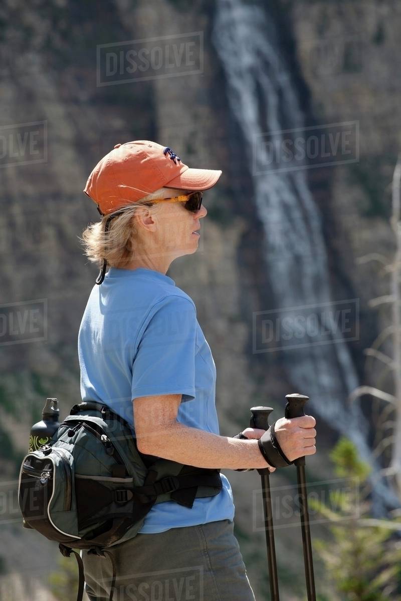 Female Hiker With A Waterfall In The Background; Waterton, Alberta ...
