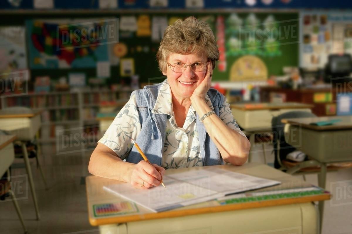 Teacher; Teacher Sitting At A Desk - Royalty-free Stock Photo | Dissolve