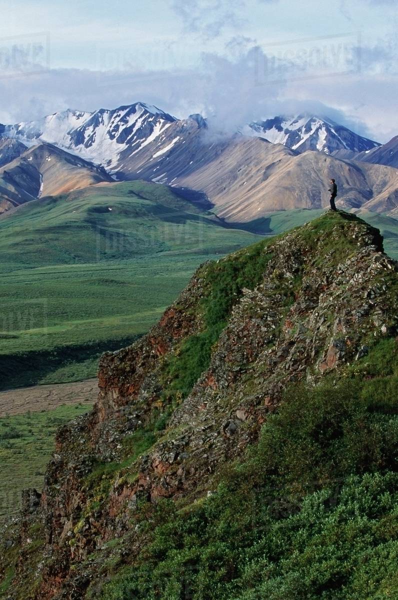 Man On Small Peak Looking At View Of Mountains And Glacial Valley ...
