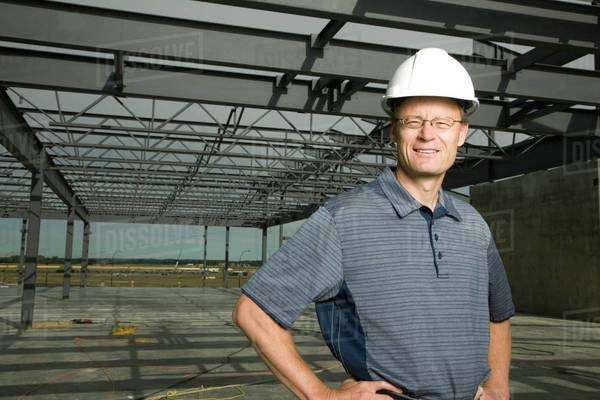 Man With A Hard Hat Standing By Building Under Construction - Royalty ...