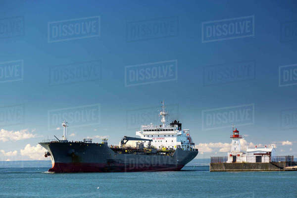 Large laker ship in water next to white and red lighthouse on at the ...