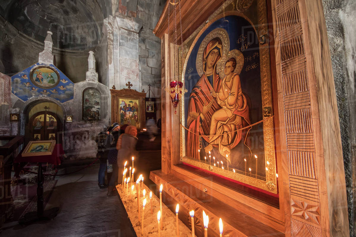 Lit candles by a Virgin and Child icon in the interior of Gergeti ...