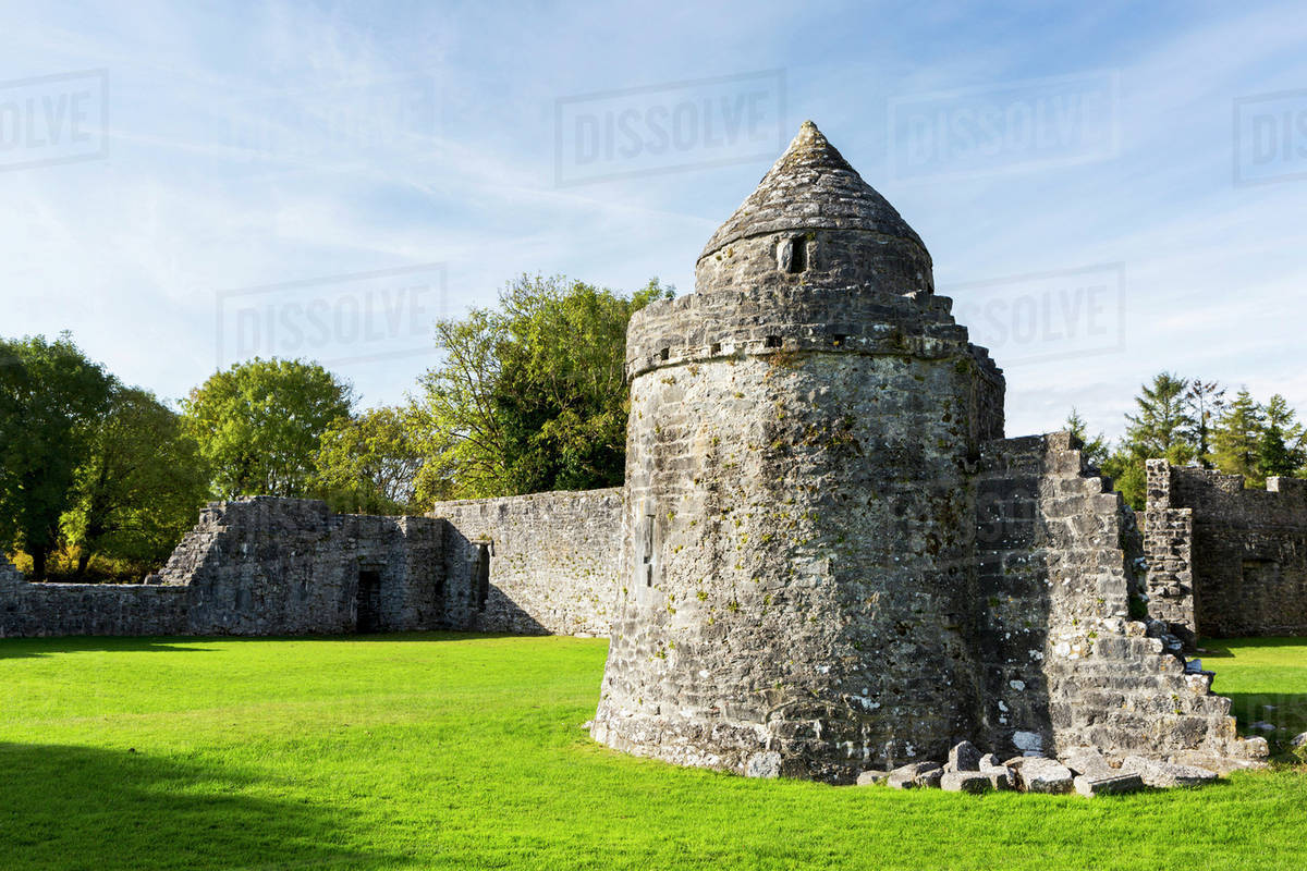 Ruins of a stone castle with stone wall and blue sky; County Galway ...