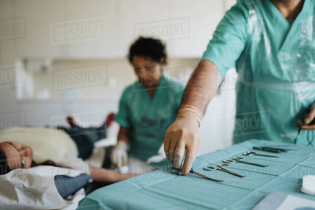 Male surgeon arranging surgical equipment on table in hospital ...
