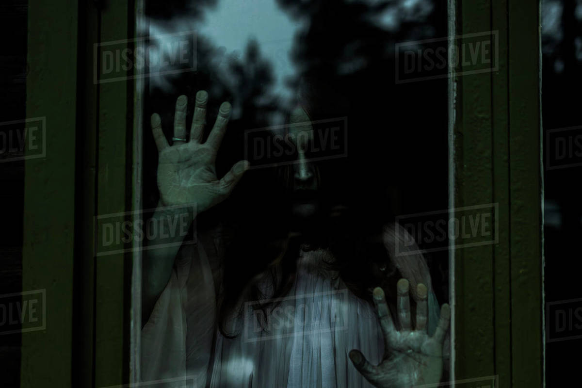 Spooky ghost looking through glass window of haunted cabin - Royalty ...