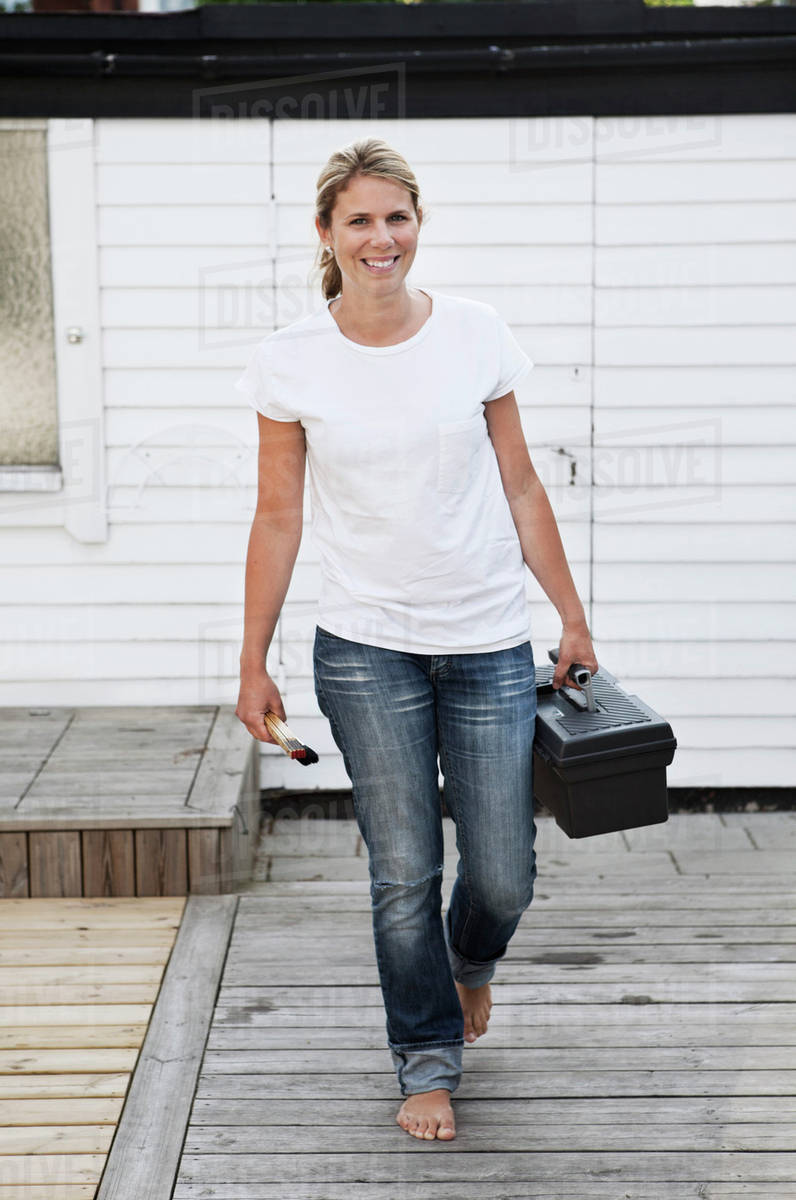 Full length of pretty woman carrying tool box - Stock Photo - Dissolve