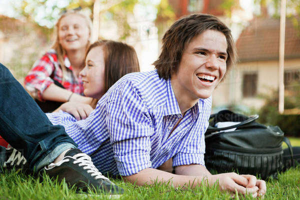 Cheerful teenage boy smiling while relaxing with friends - Stock Photo ...