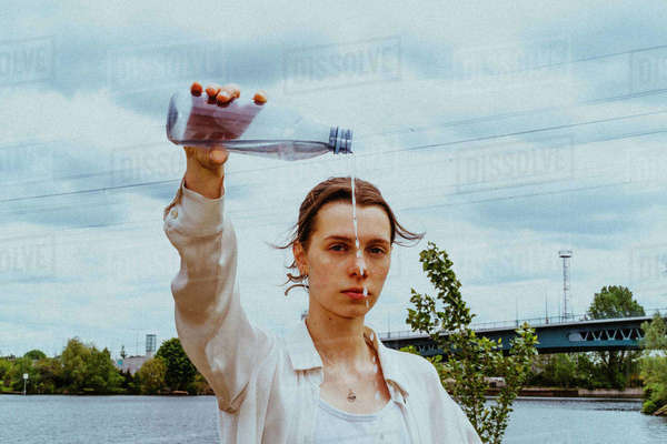 Portrait of confident young non-binary person pouring water from bottle ...
