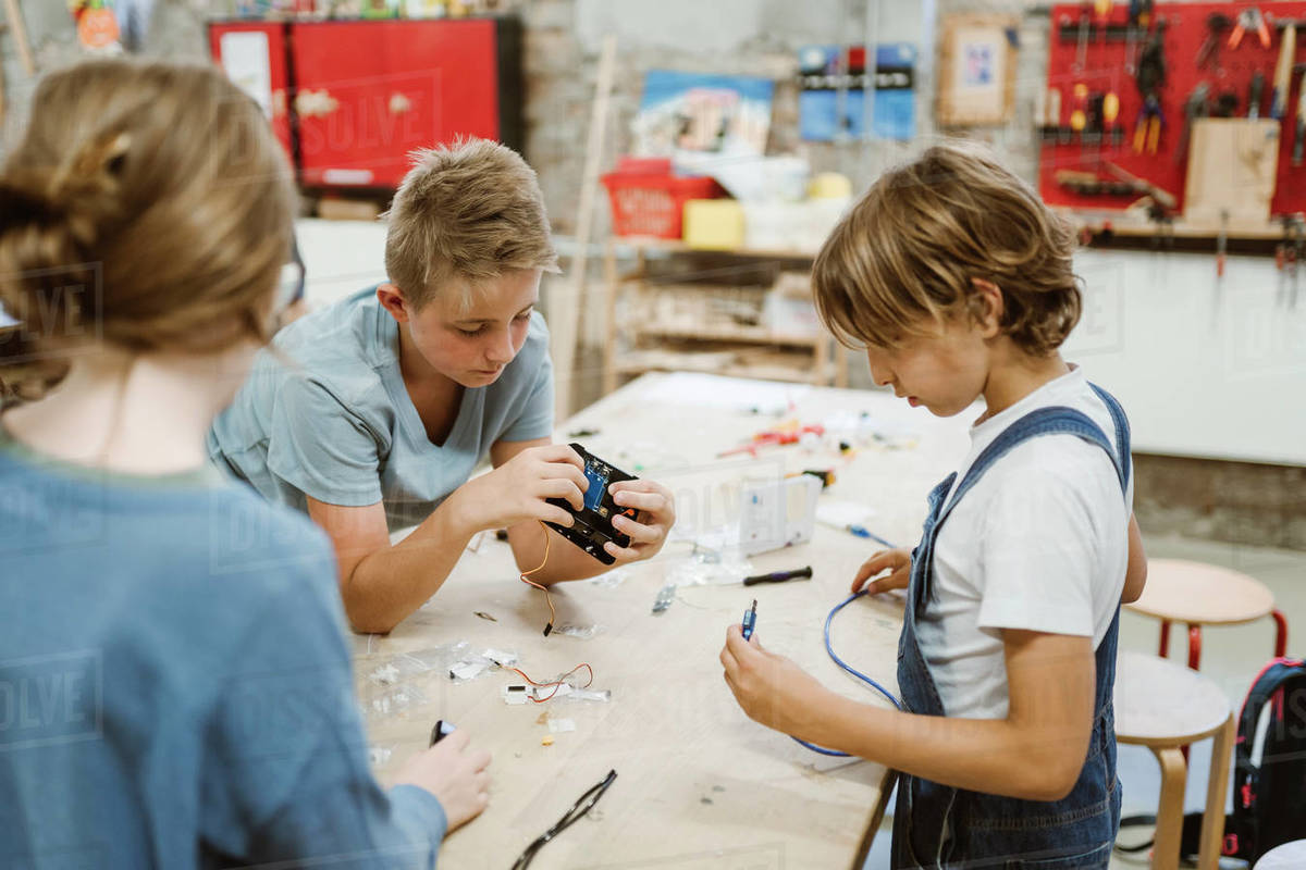 Male and female pupils working on robotics project on table in workshop ...