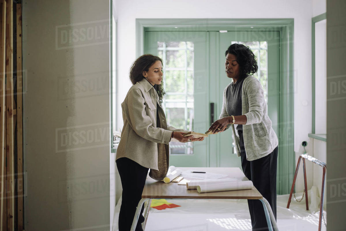 Female client comparing building material while talking with architect ...