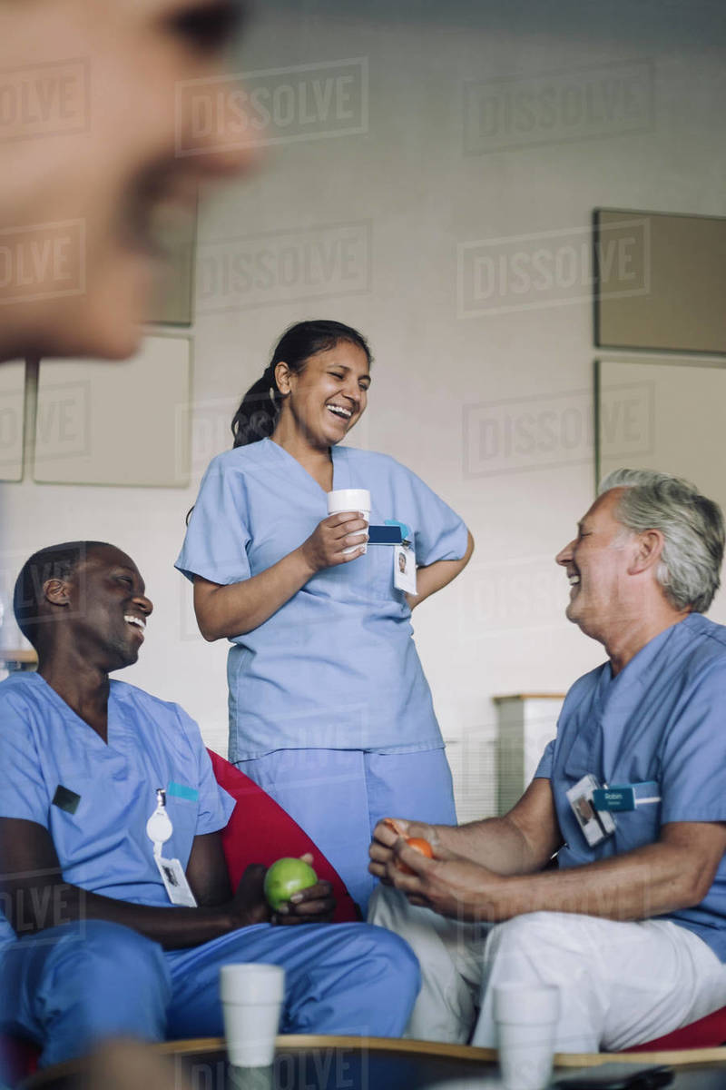 Cheerful multiracial healthcare workers talking in cafeteria of ...
