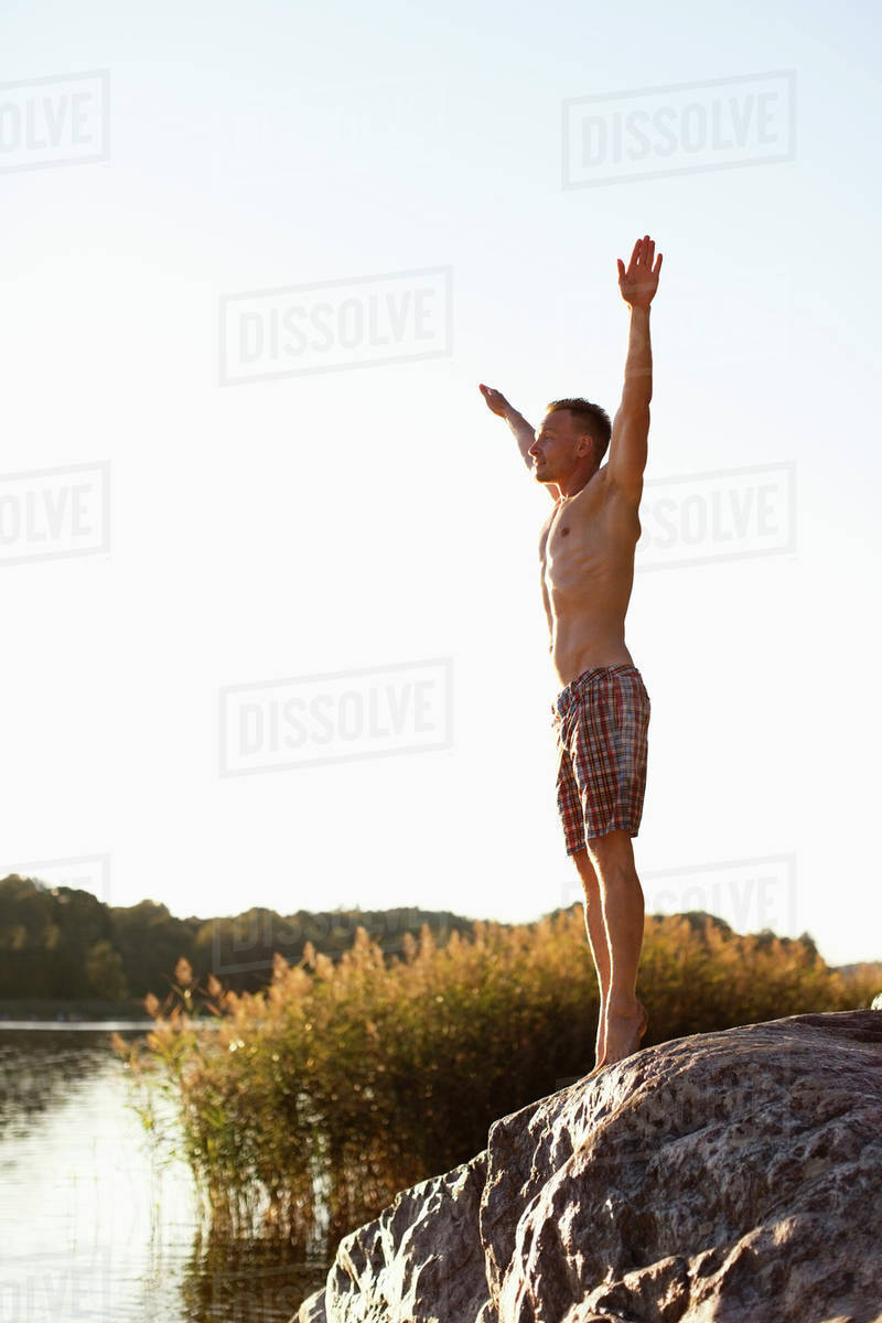 Full length of mid adult man ready to dive from rock over sky - Stock ...
